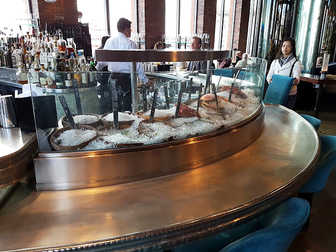 The raw bar display is seafood theater in the round—oysters lounging on ice like celebrities sunbathing on private beaches.