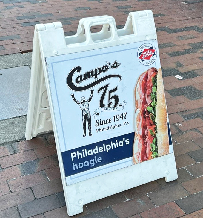 Seventy-five years of sandwich mastery advertised on a humble sidewalk sign—if only brick streets could talk about the cheesesteaks they've witnessed.