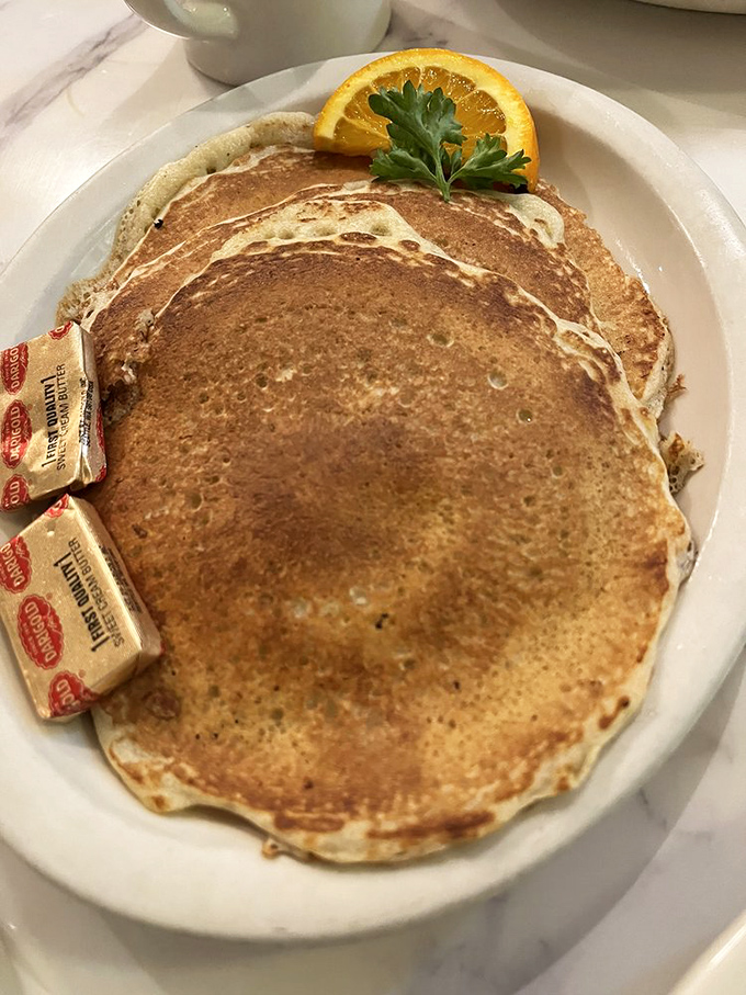These pancakes have achieved that mythical balance—edges with delicate crispness giving way to centers of pillowy perfection. The orange slice isn't garnish; it's punctuation.