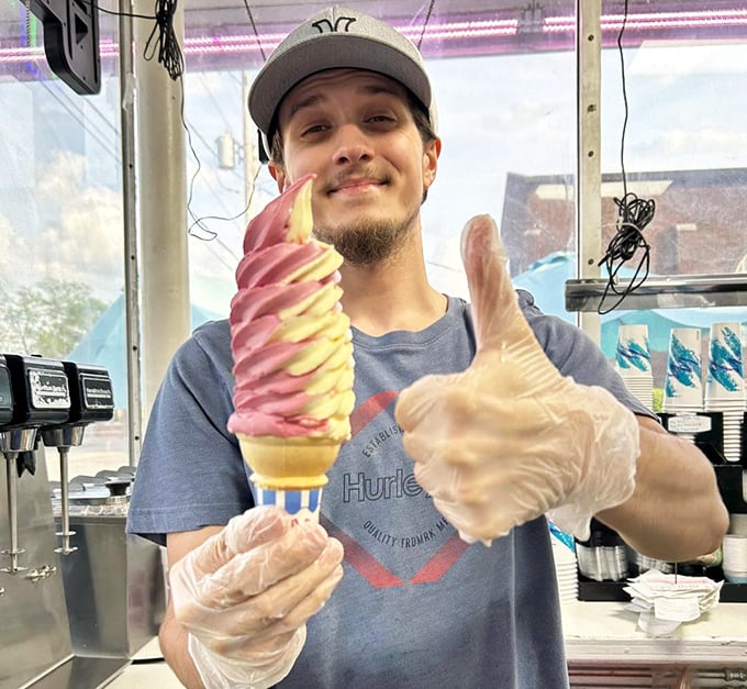 Thumbs up from the ice cream artist – his gloved hands crafting a perfect pink and white twist that defies both gravity and sadness.