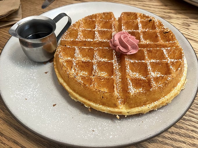 The waffle that launched a thousand food photos. Golden, crisp, and dusted with powdered sugar – it's wearing that dollop of pink butter like a tiny, delicious corsage.