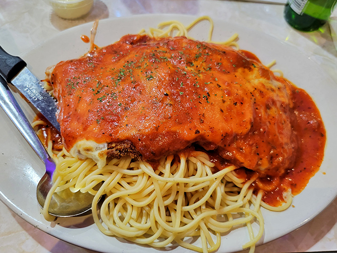 This chicken parmigiana doesn't just sit on spaghetti—it reigns over it, with sauce so rich it should have its own accountant.