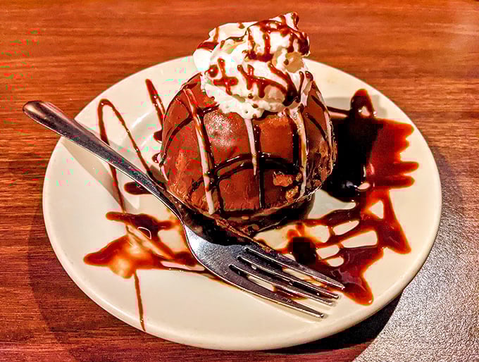 This chocolate dessert isn't just served—it's presented with the dramatic flair of a final act, drizzled with sauce that makes abstract art look delicious.