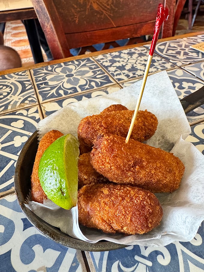 Croquetas – those golden cylinders of joy – arrive hot and crispy, ready to reveal their creamy interior secrets with one satisfying bite.