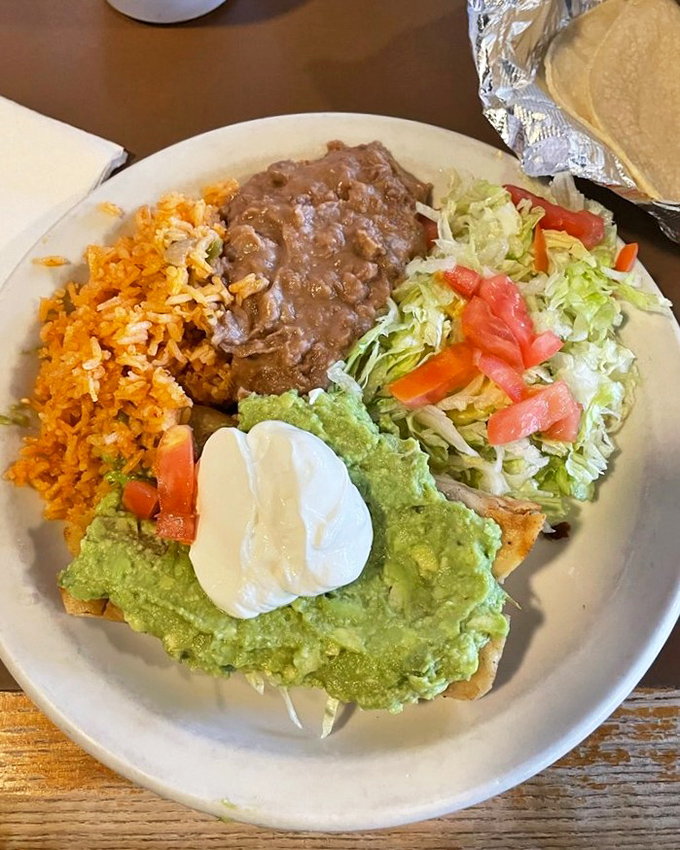 Flautas arranged like a delicious sunburst, surrounded by guacamole, sour cream, and pico de gallo – proof that the best things in life come with multiple dipping options.