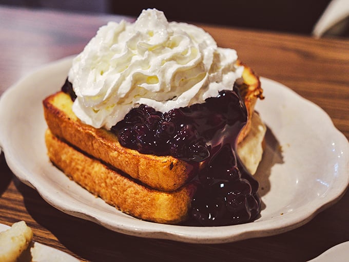 French toast that flirts with dessert territory – berry compote cascading down golden bread with a cloud of whipped cream playing matchmaker.