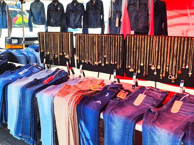 Jewelry displayed with democratic flair—gold crosses and pendants dangling above denim arranged in a rainbow of blue possibilities.