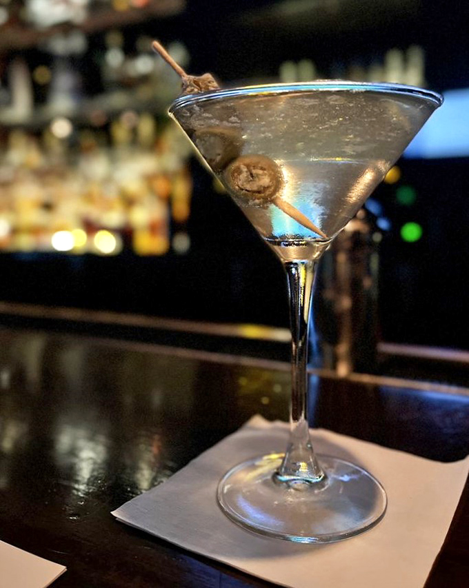The martini arrives crystal clear with blue-cheese-stuffed olives – a sophisticated handshake before the main event begins.