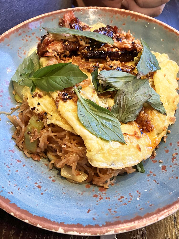 Not Pad Thai indeed—this noodle dish with its fresh basil crown refuses to be ordinary, and your taste buds are better for it.