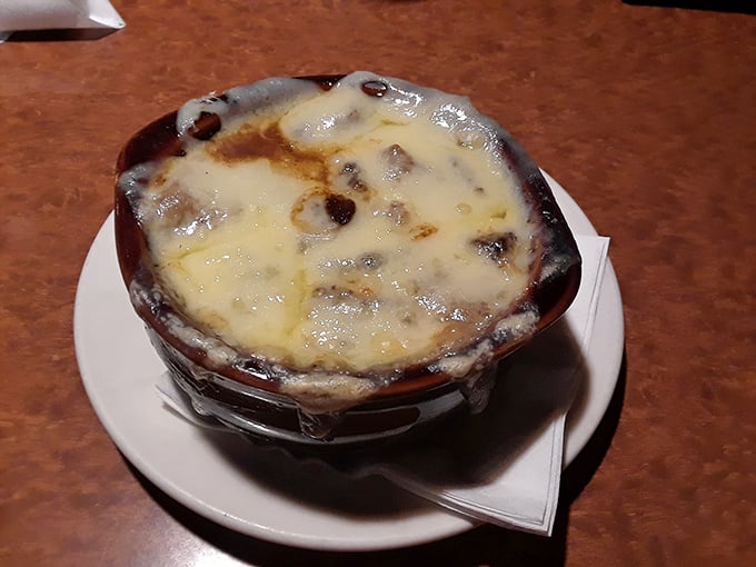 This isn't just onion soup—it's a bubbling cauldron of comfort topped with a golden cheese cap that stretches dramatically with each spoonful.