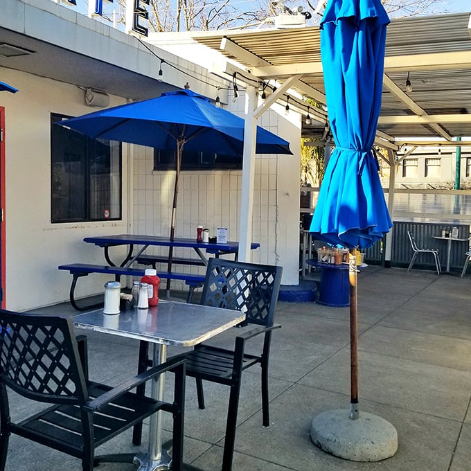 The outdoor patio offers urban oasis vibes with blue umbrellas providing shade for those who prefer their breakfast with a side of fresh air.