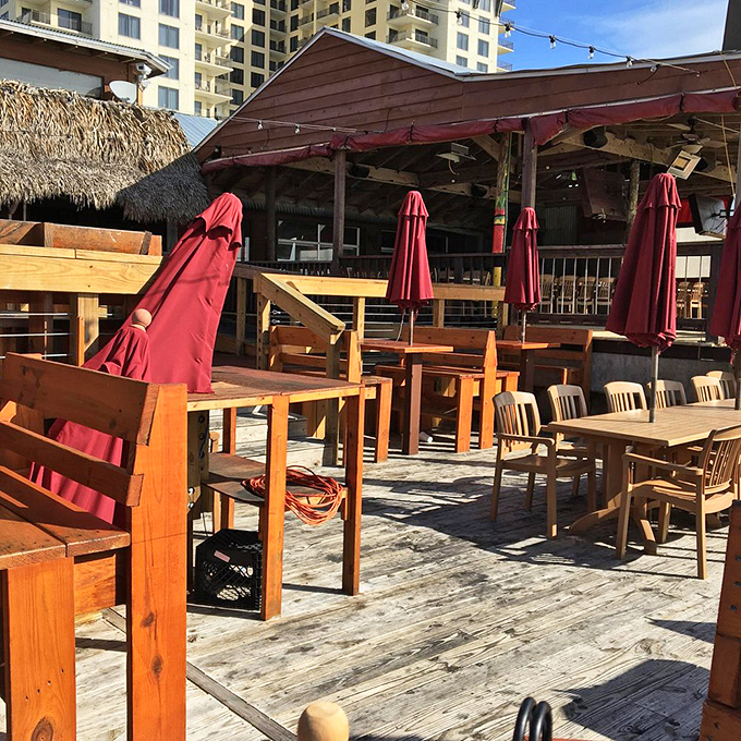 The outdoor dining area—where the Gulf breeze serves as both air conditioning and appetite enhancer. Those red umbrellas? Just showing off.