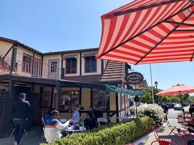 Al fresco dining under cheerful red-striped umbrellas—where pastry consumption becomes a spectator sport for envious passersby.