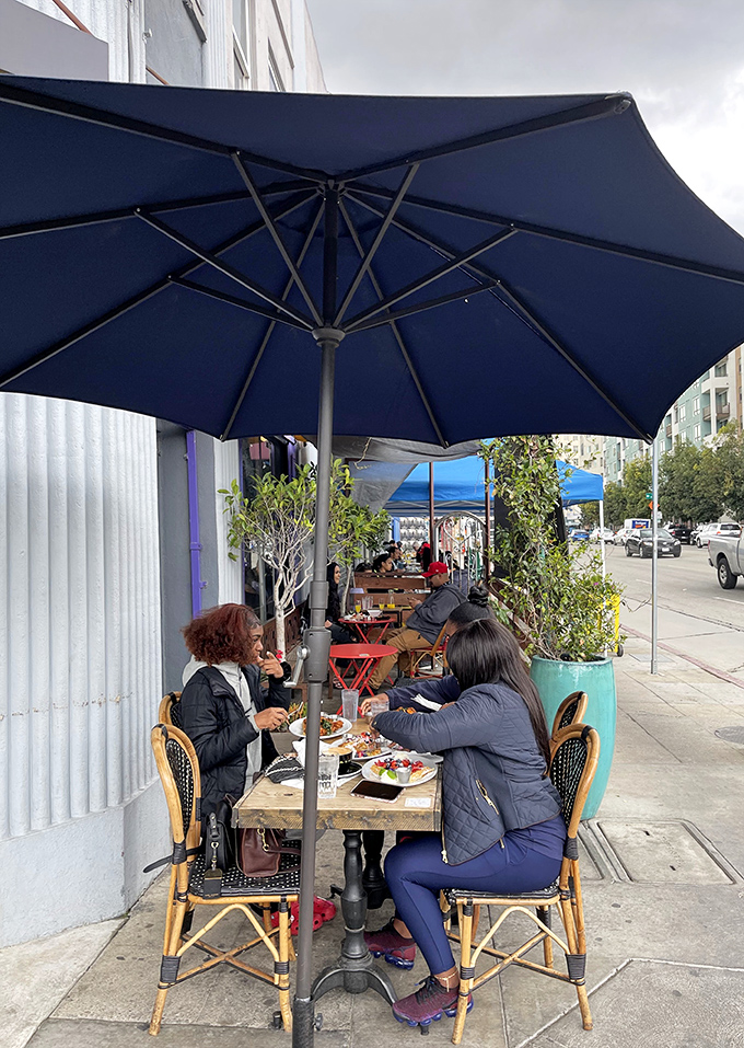 Sidewalk dining under blue umbrellas – because waffles taste even better with a side of people-watching and fresh LA air.