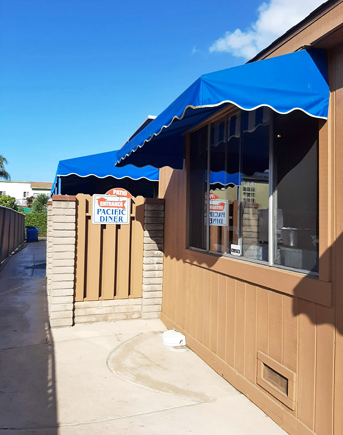 The patio entrance beckons with its wooden gate and signature blue awning—a portal to comfort food paradise.