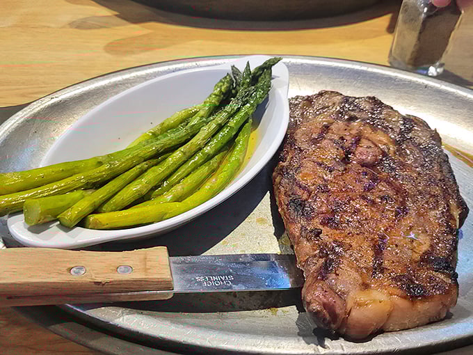 A perfectly cooked ribeye alongside bright asparagus spears. The knife stands ready for the most satisfying cut you'll make all week.