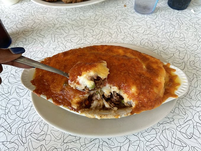 Beneath that golden crust lies a savory treasure of seasoned beef and vegetables—comfort food archaeology at its most delicious.