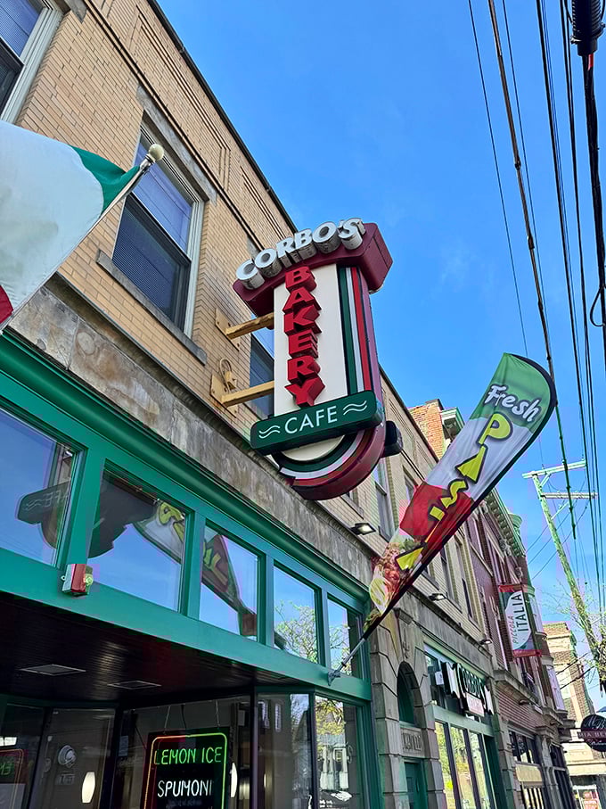 The vertical neon sign announces "Corbo's Bakery" like a sweet siren call. The "Lemon Ice" sign below promises refreshment that no chain store could possibly match.