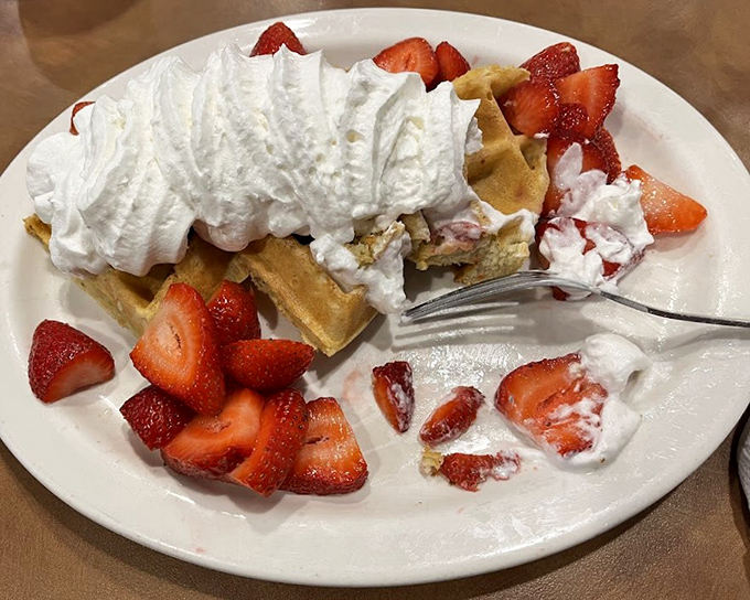 Strawberry waffles that blur the line between breakfast and dessert—a mountain of whipped cream that would make any dietitian look the other way.