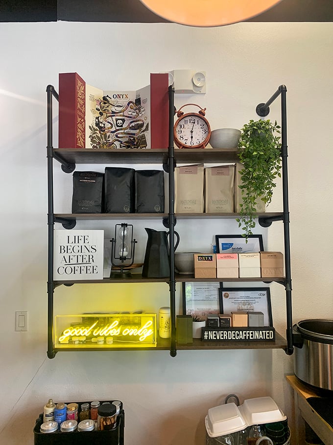 "Life begins after coffee" proclaims the shelf décor, while the neon "good vibes only" sign below makes a compelling argument for morning optimism.