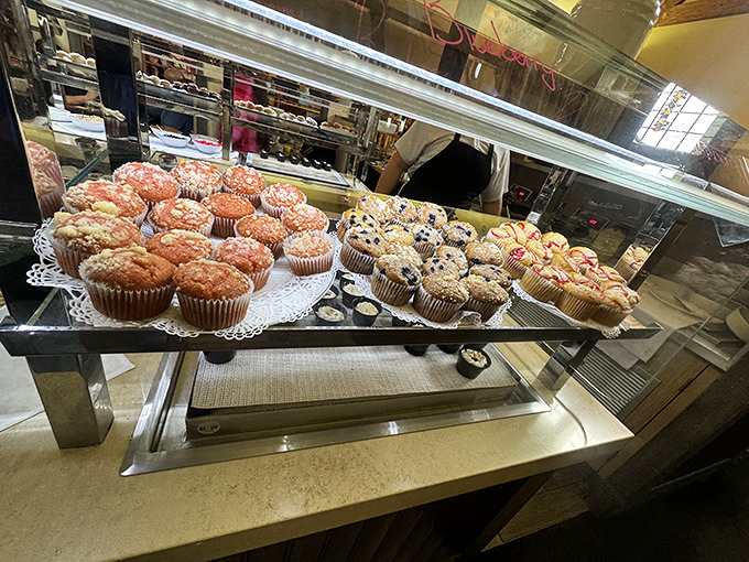 Muffin mountains behind glass—the dessert tease that has you planning your buffet strategy backward. "Save room" becomes your internal mantra.