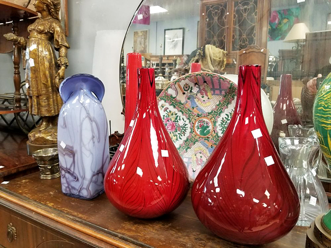 Those red glass vases aren't just decorative – they're statement pieces that transform a boring shelf into an art installation.