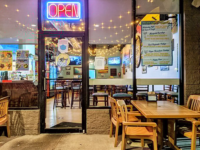 The neon "OPEN" sign might as well say "PARADISE" – peek through these doors and glimpse the warm, string-lit sanctuary of flavor waiting inside.