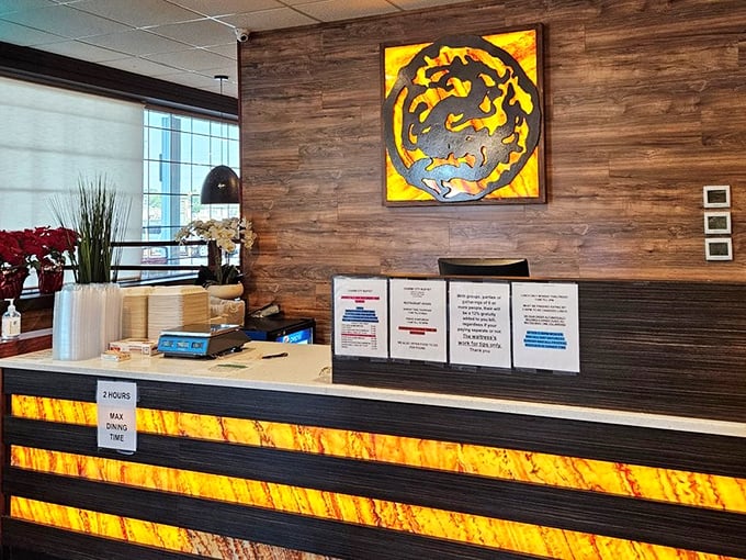 The reception desk – your gateway to gluttony. That amber-lit dragon logo isn't just decoration; it's a warning of the fire your taste buds are about to experience.