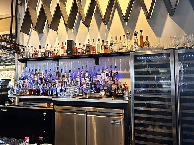 Behind the bar, bottles stand at attention like soldiers guarding liquid treasure. The diagonal wall feature adds architectural intrigue worthy of conversation.