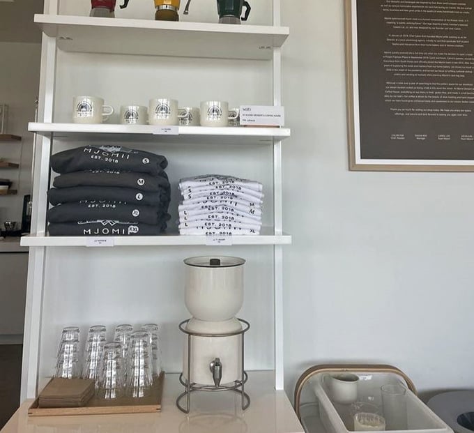 Even the merchandise display maintains the minimalist aesthetic. Those mugs aren't just vessels for coffee—they're souvenirs of sweetness.