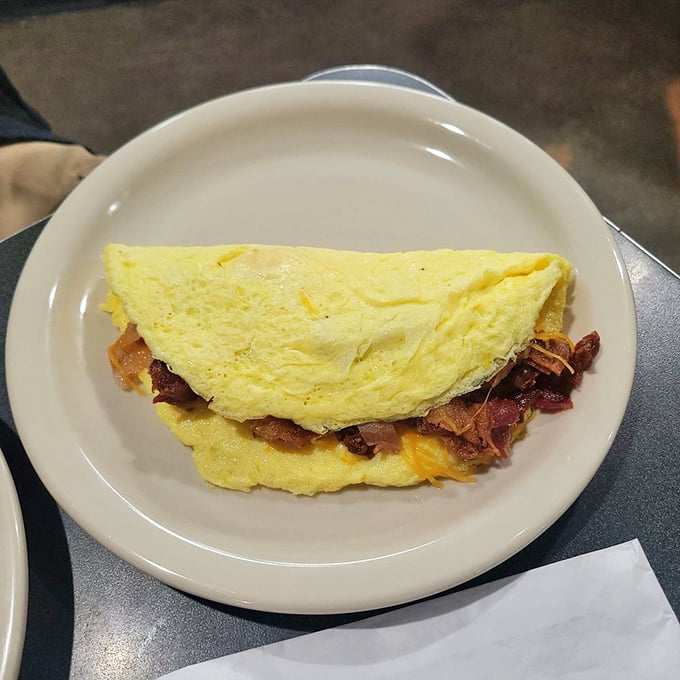 This omelet doesn't just contain bacon—it celebrates it. Folded yellow perfection housing a smoky, crispy treasure within.