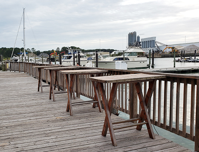 Weathered wooden high-tops along the deck—where strangers become friends over shared plates and harbor stories.