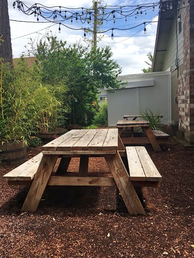 The outdoor seating area, with its rustic picnic tables and string lights, creates the perfect stage for the drama of good eating.