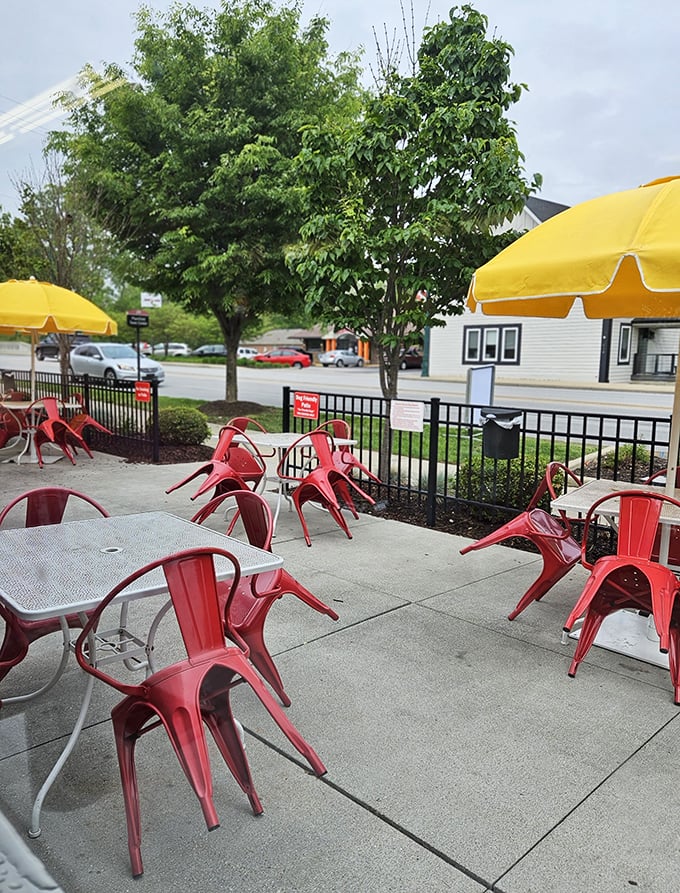 Red metal chairs and yellow umbrellas create an outdoor dining space that's both retro and timeless—like finding a 1950s postcard brought to life.
