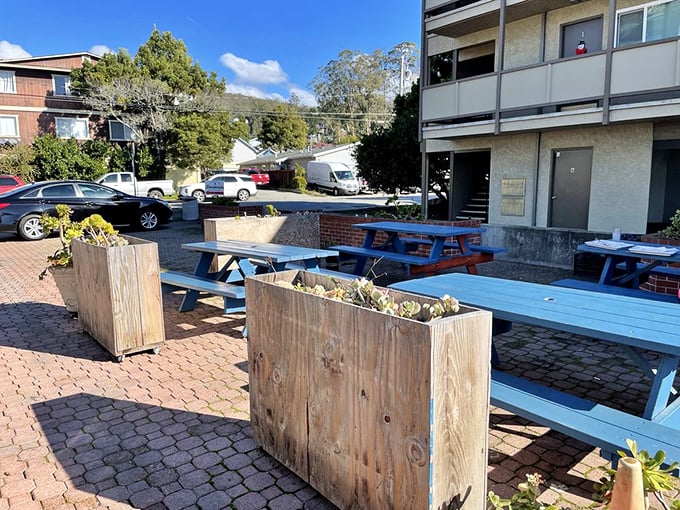 The outdoor seating area offers a breath of fresh coastal air between bites of smoky perfection. Blue picnic tables invite lingering conversations.