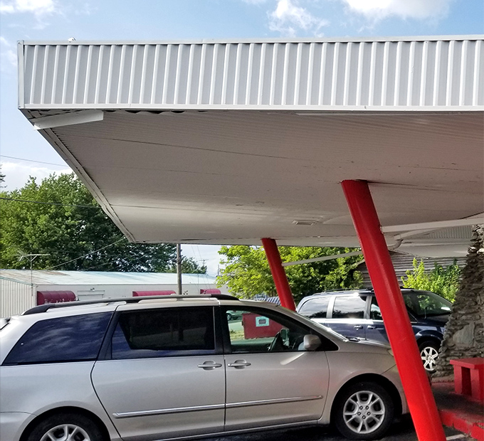 The covered parking area welcomes vehicles of all makes and models—a democratic approach to dining where your car's price tag doesn't determine your tenderloin quality.