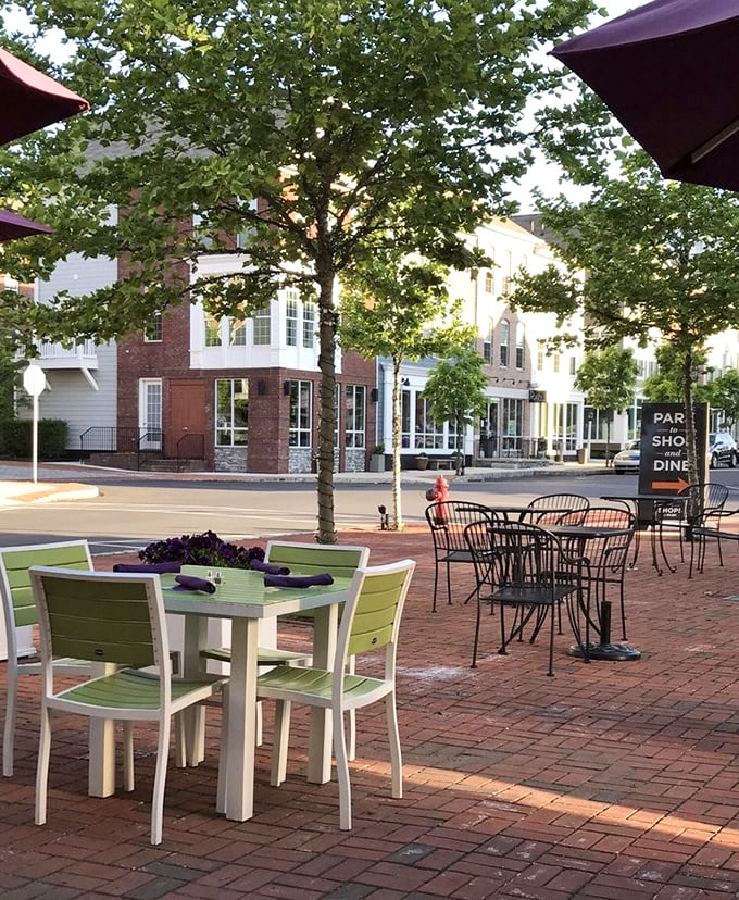 Outdoor dining that captures the essence of small-town charm – brick pathways, green chairs, and the gentle rustle of leaves overhead.