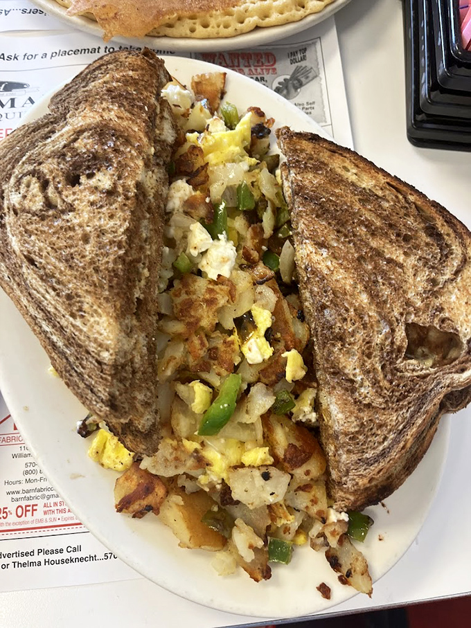 Breakfast engineering at its finest: Crispy toast barely containing a mountain of perfectly seasoned potatoes, eggs, and peppers.