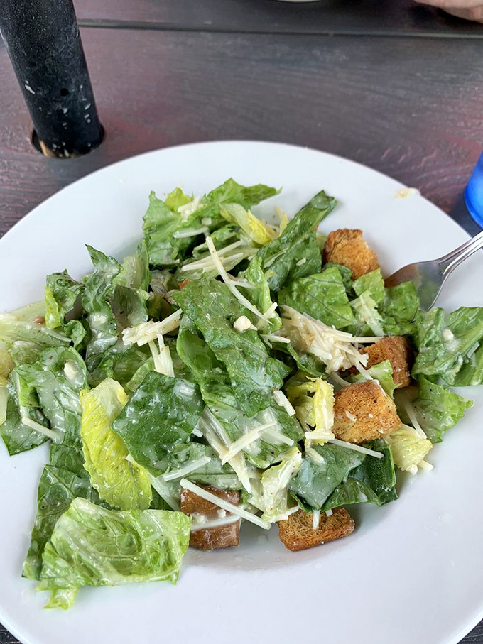 Even the salad looks happy to be here, crisp romaine mingling with croutons and cheese like guests at the world's freshest party.