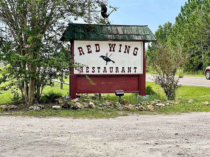 The roadside sign stands as a beacon to hungry travelers – a promise of good things to come just down the gravel drive.
