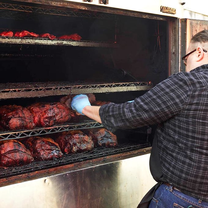 A pitmaster's hands tell stories that words never could. This careful tending of meat in the smoker isn't just cooking—it's a time-honored ritual of transformation.