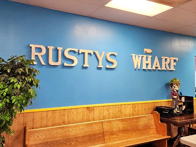 The blue wall proudly displays the Rusty's Wharf name, while a wooden bench invites you to take a seat if there's a wait—there often is.