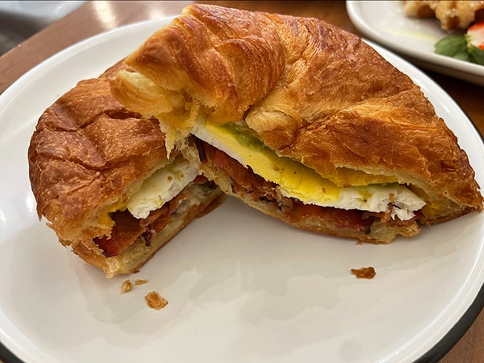 The breakfast sandwich in its final form – a croissant creation cut in half to reveal the architectural marvel of egg, bacon and cheese within.