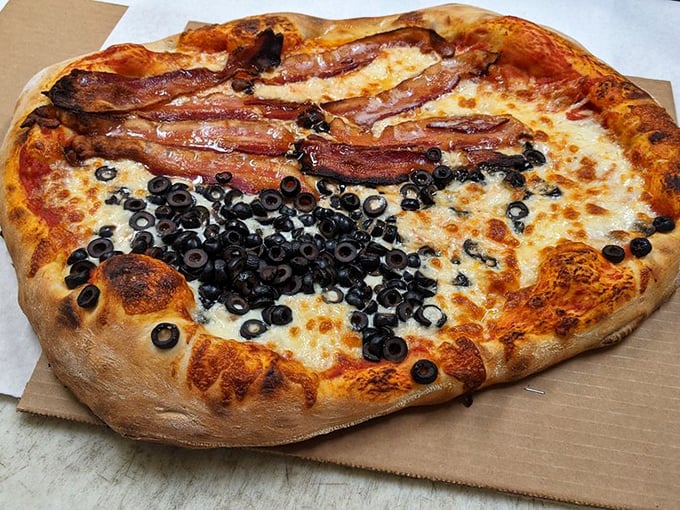 Bacon strips laid with architectural precision atop a sea of olives and cheese. This isn't just a pizza—it's a statement piece.