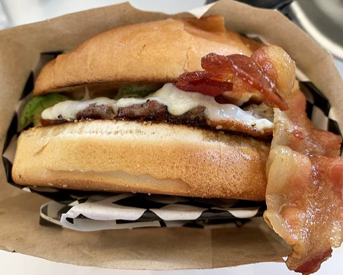This isn't just a burger—it's a masterclass in proper bacon draping. The melty cheese and fresh toppings are ready for their close-up.