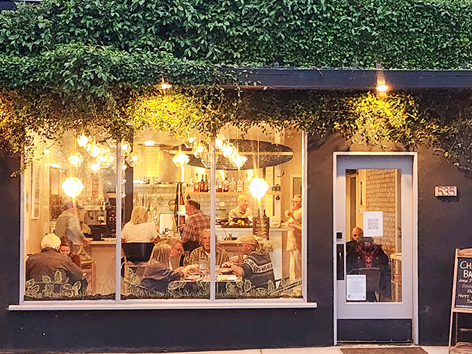 This cozy restaurant window frames the perfect retirement evening – good food, warm light, and not a single urgent email in sight.