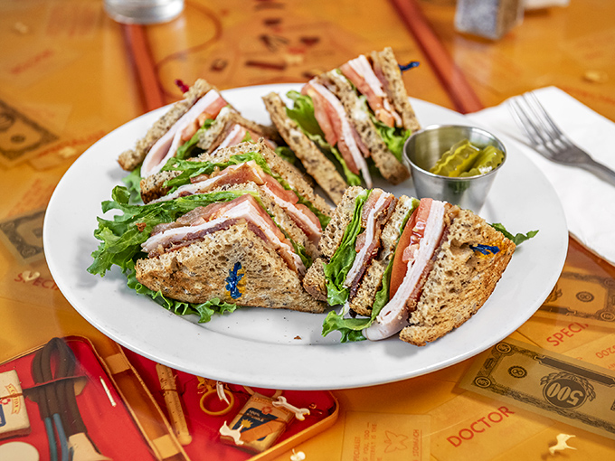 The club sandwich—architecture's greatest contribution to lunch. Layers of goodness held together by toothpicks and optimism, with pickles standing guard.
