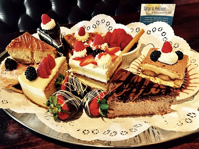 The dessert platter arrives like a sweet fever dream—a parade of cakes, tarts, and chocolate-dipped strawberries that makes sharing both necessary and slightly heartbreaking.