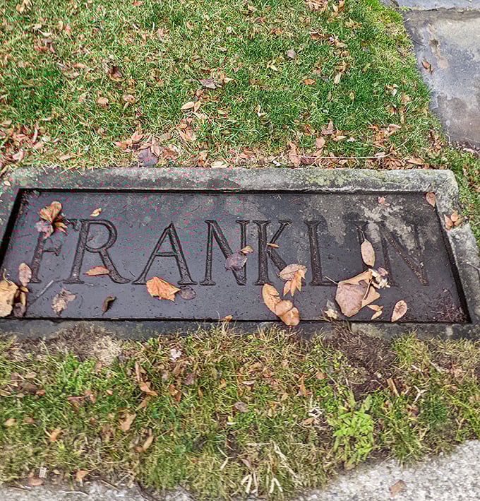 A simple stone marker embedded in the lawn, autumn leaves gathering around the letters that spell out the legacy of Franklin.