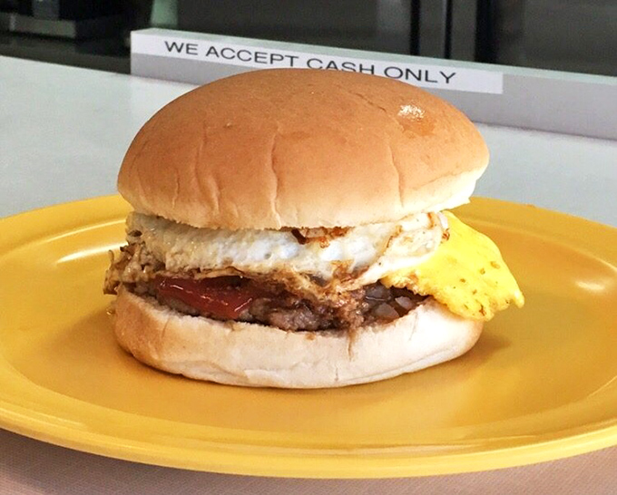 The breakfast sandwich that launches a thousand productive mornings. Egg, meat, and cheese on a soft bun—simple perfection on a yellow plate.